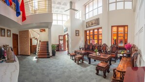 Um hall espaçoso com teto alto, escadaria e área de estar com mobiliário de madeira.