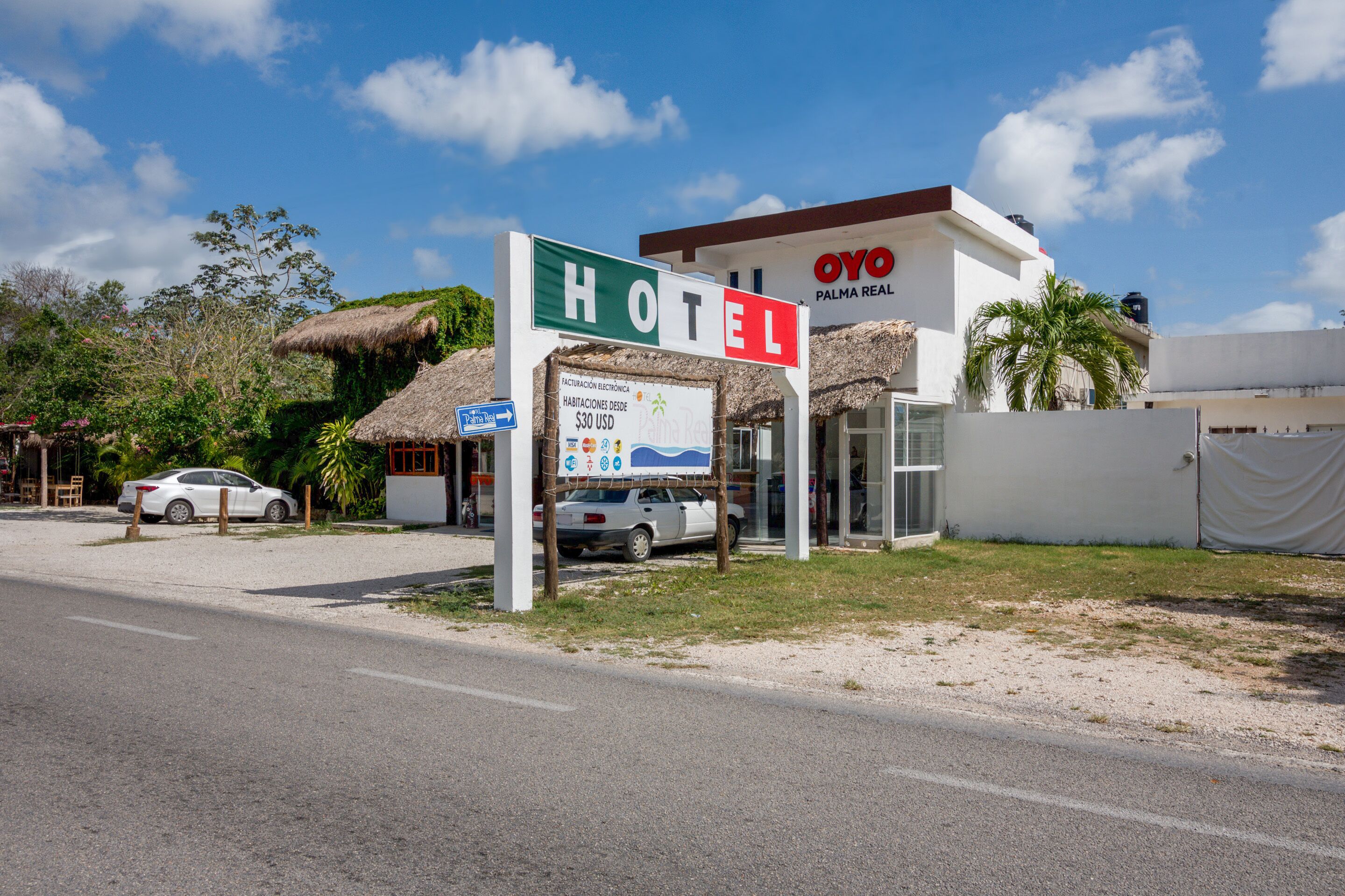 Um hotel chamado "OYO Palma Real", com uma placa indicando um preço de 30 dólares.