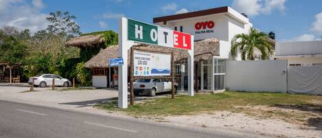 Um hotel chamado "OYO Palma Real", com uma placa indicando um preço de 30 dólares.