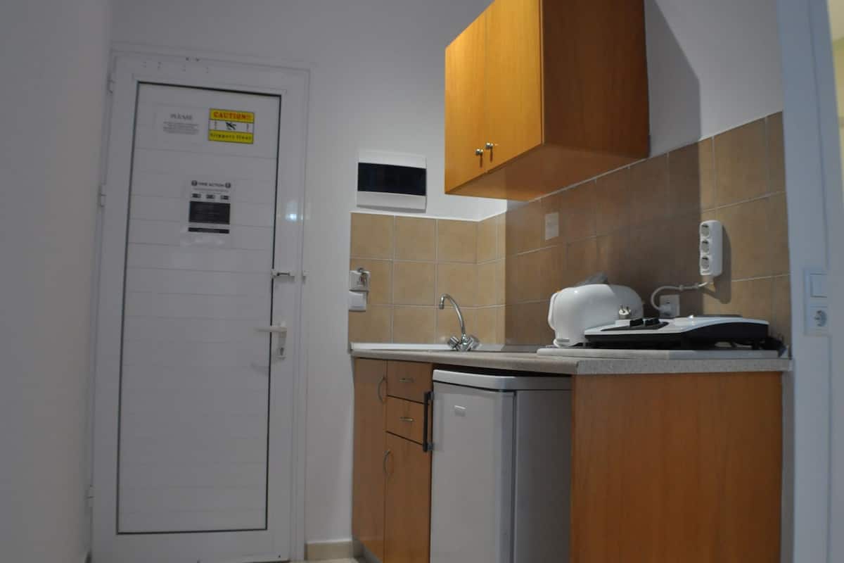 Uma cozinha compacta com máquina de lavar louça embutida, armários de madeira e uma porta branca com sinal de segurança.