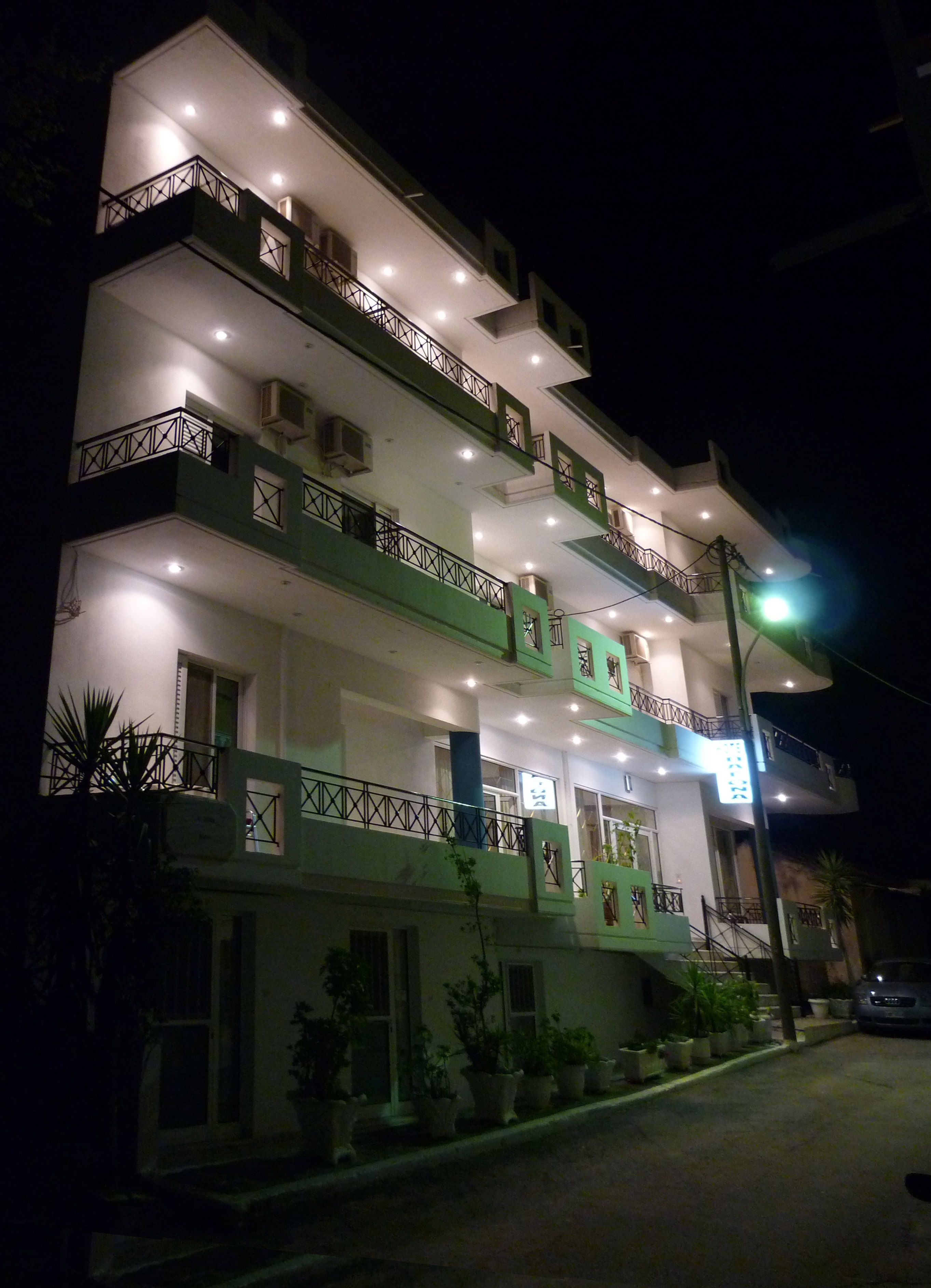 Um edifício com vários andares, varandas, aparelhos de ar condicionado e plantas em vasos.