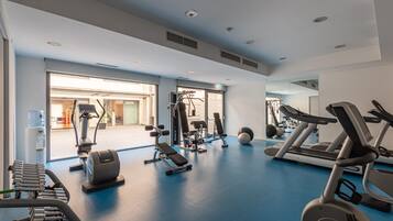 Academia com máquinas de cardio, estação de musculação e bebedouro.