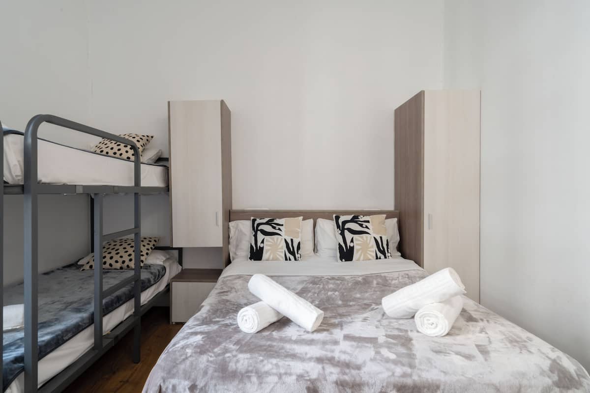 Quarto com beliches, uma cama com toalhas enroladas e um guarda-roupa.