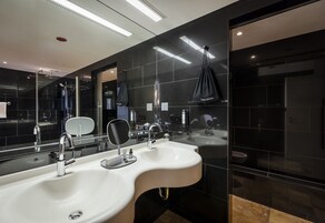 Casa de banho moderna com um espelho grande, duas pias e um secador de cabelo pendurado na parede.