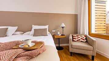 Quarto de hotel com cama, mesa de cabeceira, cadeira e janela com persianas.