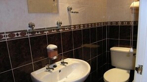 Casa de banho com lavatório branco, sanita e chuveiro.