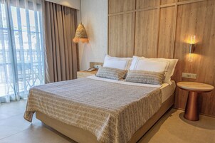 Quarto de hotel moderno com uma cama grande, painéis de madeira e vista para o exterior.