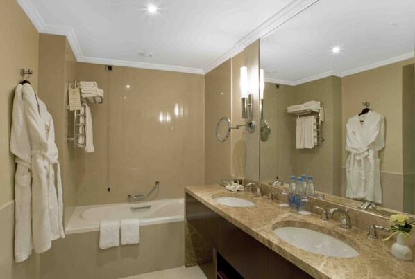 Uma casa de banho moderna com duas bacias, uma banheira e um espelho grande.