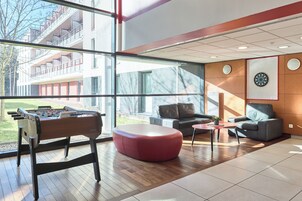 Um interior moderno com mesa de futebol, sofás de couro e dardos.