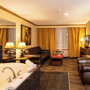 Quarto de hotel com uma cama grande, um sofá, uma mesa de centro e uma televisão.