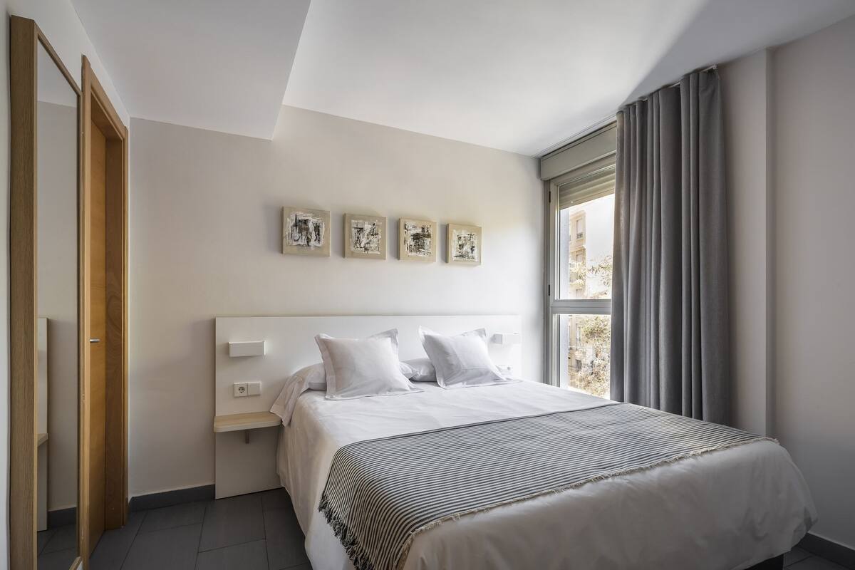 Quarto moderno com uma cama grande, um guarda-roupa de madeira e três quadros abstratos na parede.