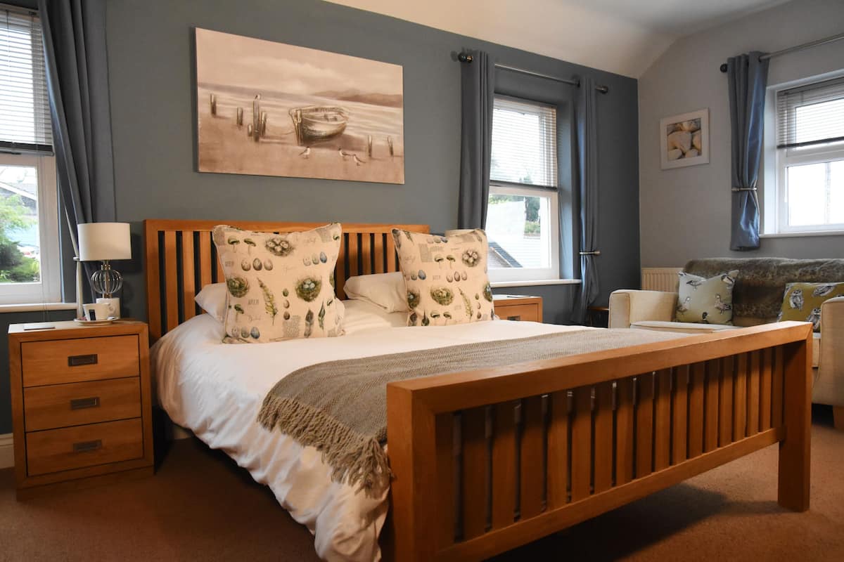 Quarto com cama de madeira, mesa de cabeceira e janela com cortinas.