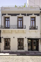 Um edifício de dois andares com arquitetura clássica, com varandas ornamentadas e grandes janelas.
