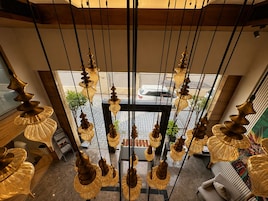Um interior moderno com luminárias pendentes, vista através de uma grande janela e um espaço de estar com um sofá.