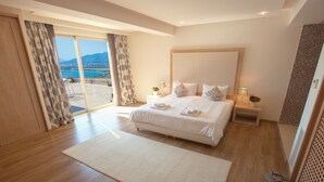 Um quarto espaçoso com uma cama grande, vista para o mar e varanda.