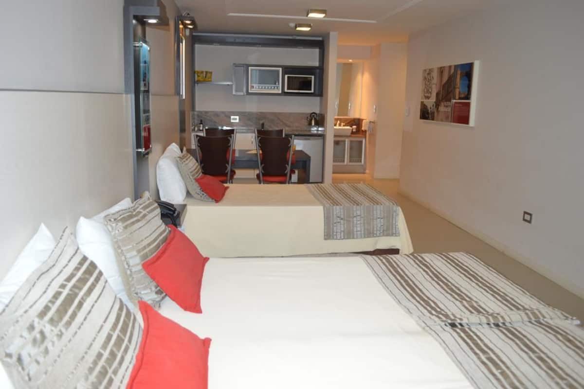 Quarto com duas camas, uma kitchenette e um banheiro.