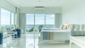 Quarto de hotel espaçoso com uma cama grande, um sofá e varanda com vista para o mar.