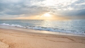 Uma praia com ondas e céu nublado.
