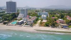 Um hotel à beira-mar com vários edifícios, piscina e praia.