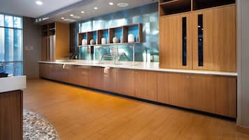 Uma cozinha moderna com armários de madeira, bancada de mármore e uma estante embutida com objetos decorativos.