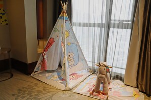 Uma tenda de brincadeira infantil com personagens de desenhos animados, um brinquedo de pelúcia e um tapete estampado no chão.