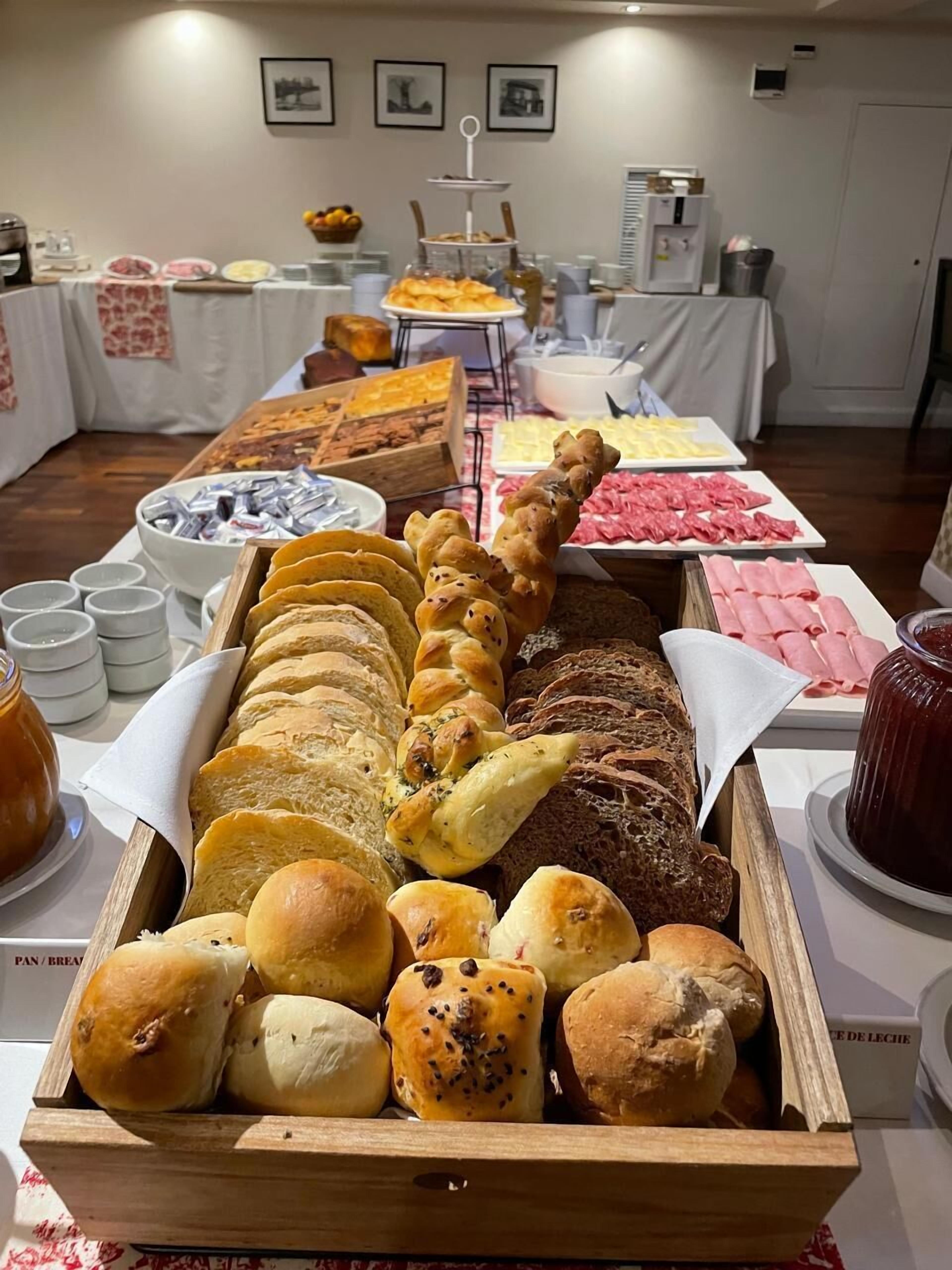 Uma mesa de buffet com diversos pães, bolos e carnes.