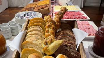 Uma mesa de buffet com diversos pães, bolos e carnes.