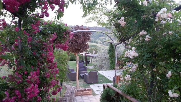 Caminho no jardim que leva a área de estar externa, com pérgola e vista para uma paisagem montanhosa.