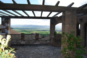 Uma construção de pedra com pérgola de madeira, oferecendo vista para uma paisagem rural.