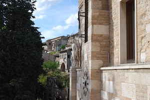 Um edifício histórico de pedra com janelas em arco e uma estátua.