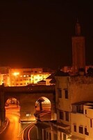 Vista noturna de uma paisagem urbana com uma torre imponente e uma ponte.