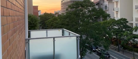 Uma varanda com vista para um canteiro de obras e uma rua com carros estacionados.