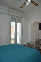 Quarto com cama, ventoinha no teto, guarda-roupa e vista para o exterior.