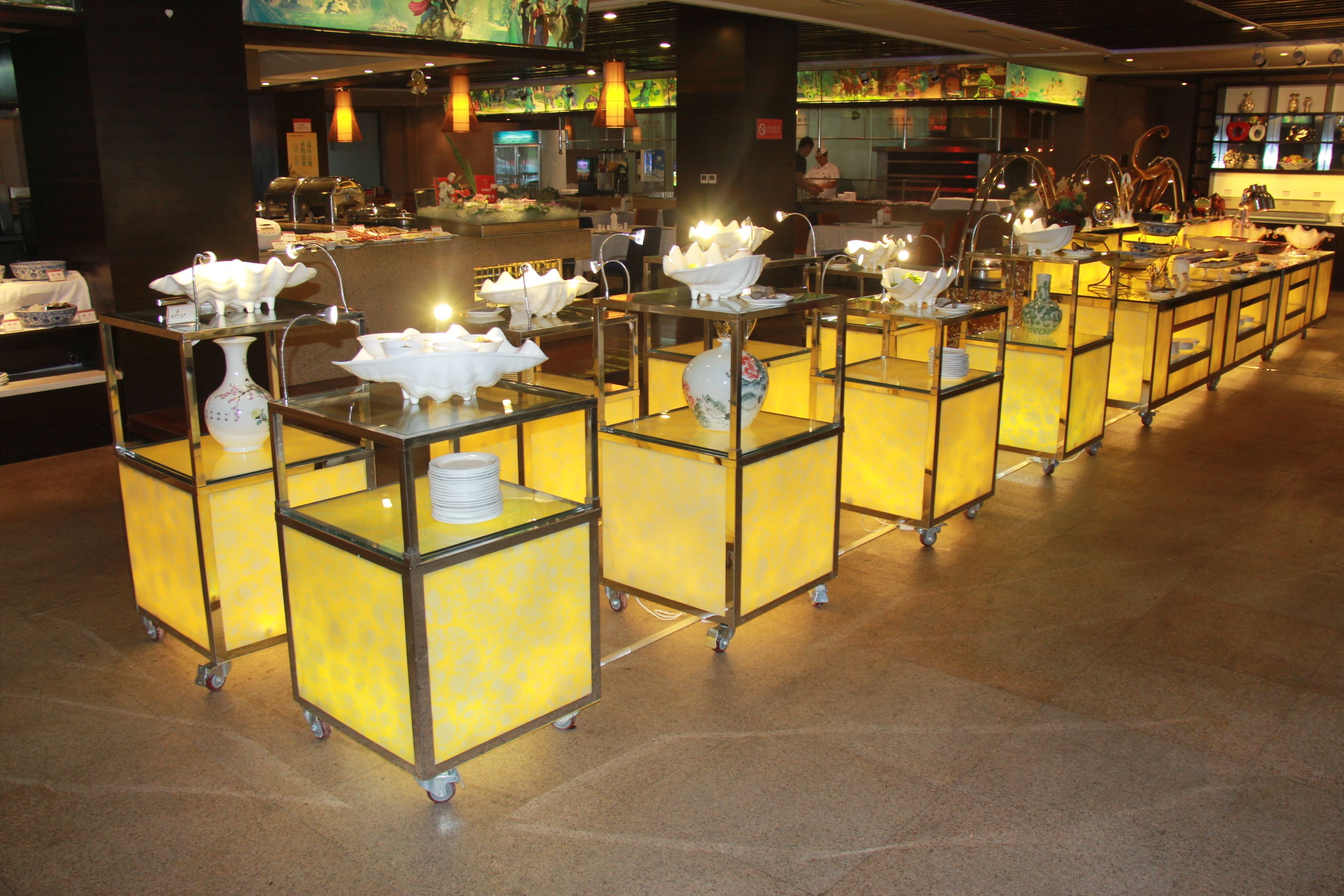 Disposição de buffet com várias estações de comida, cada uma com uma vitrine de vidro e uma tigela branca.
