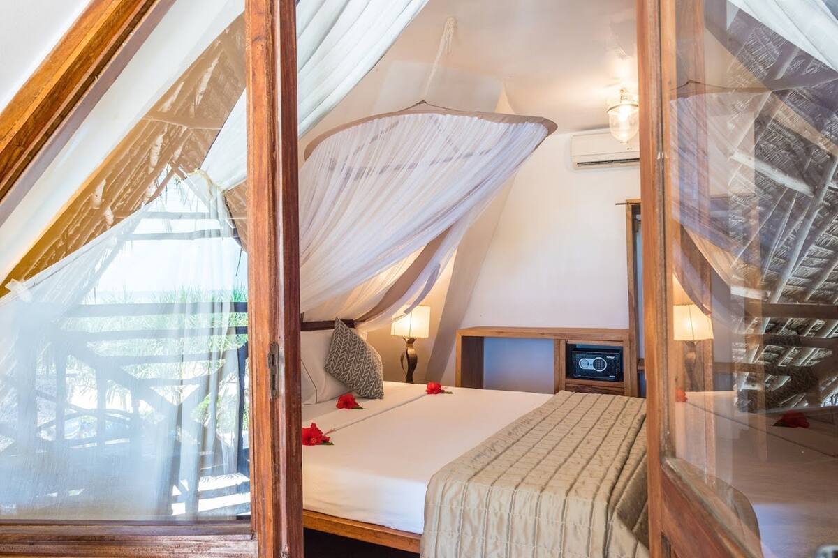 Quarto com cama, mesa de cabeceira, abajur e ventilador de teto.