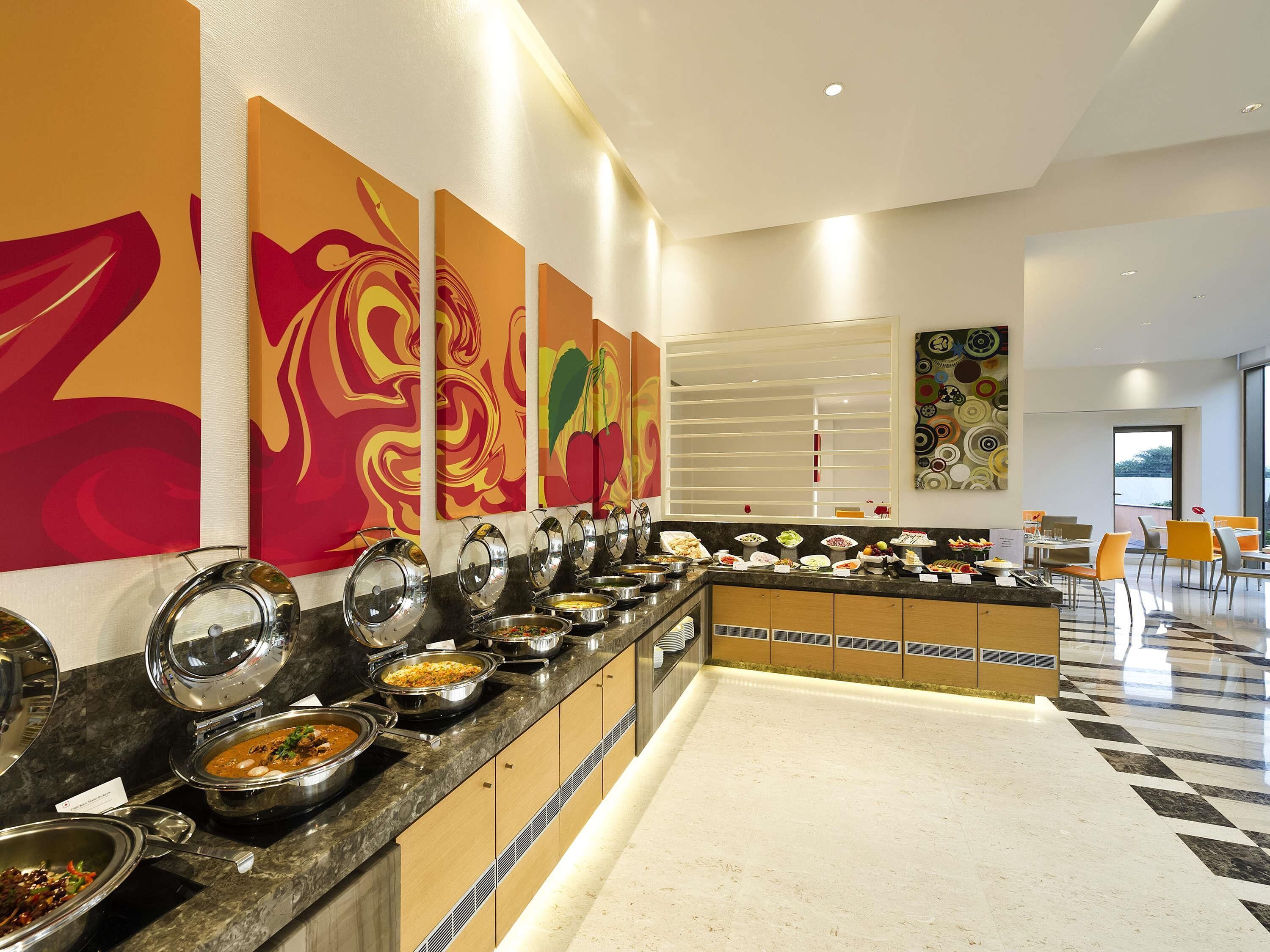 Um buffet com diversos pratos, uma área de estar com mesas e cadeiras e arte abstrata nas paredes.