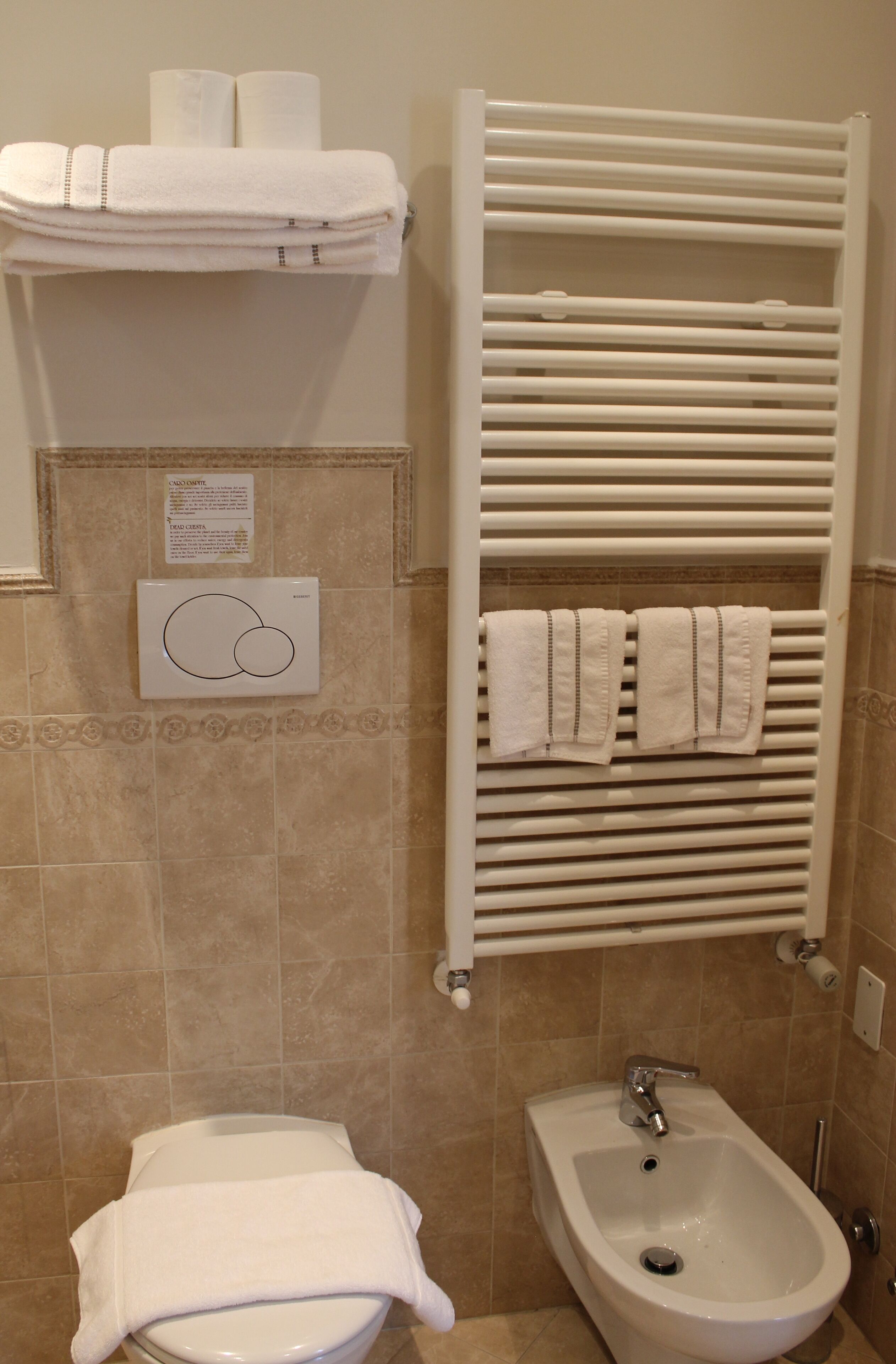 Casa de banho com sanita, bidé, porta-toalhas e placa a indicar o tipo de quarto.
