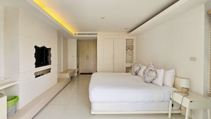Quarto moderno com uma cama grande, televisão fixada na parede e closet espaçoso.