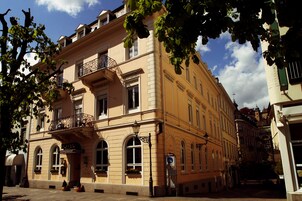 Um edifício histórico com varanda, janelas em arco e uma placa indicando que é um hotel.