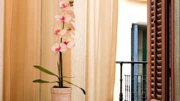 Uma orquídea em vaso sobre uma mesa num quarto com varanda e porta de madeira.