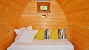 Um quarto de cabana de madeira aconchegante, com cama, almofadas e uma pequena janela.
