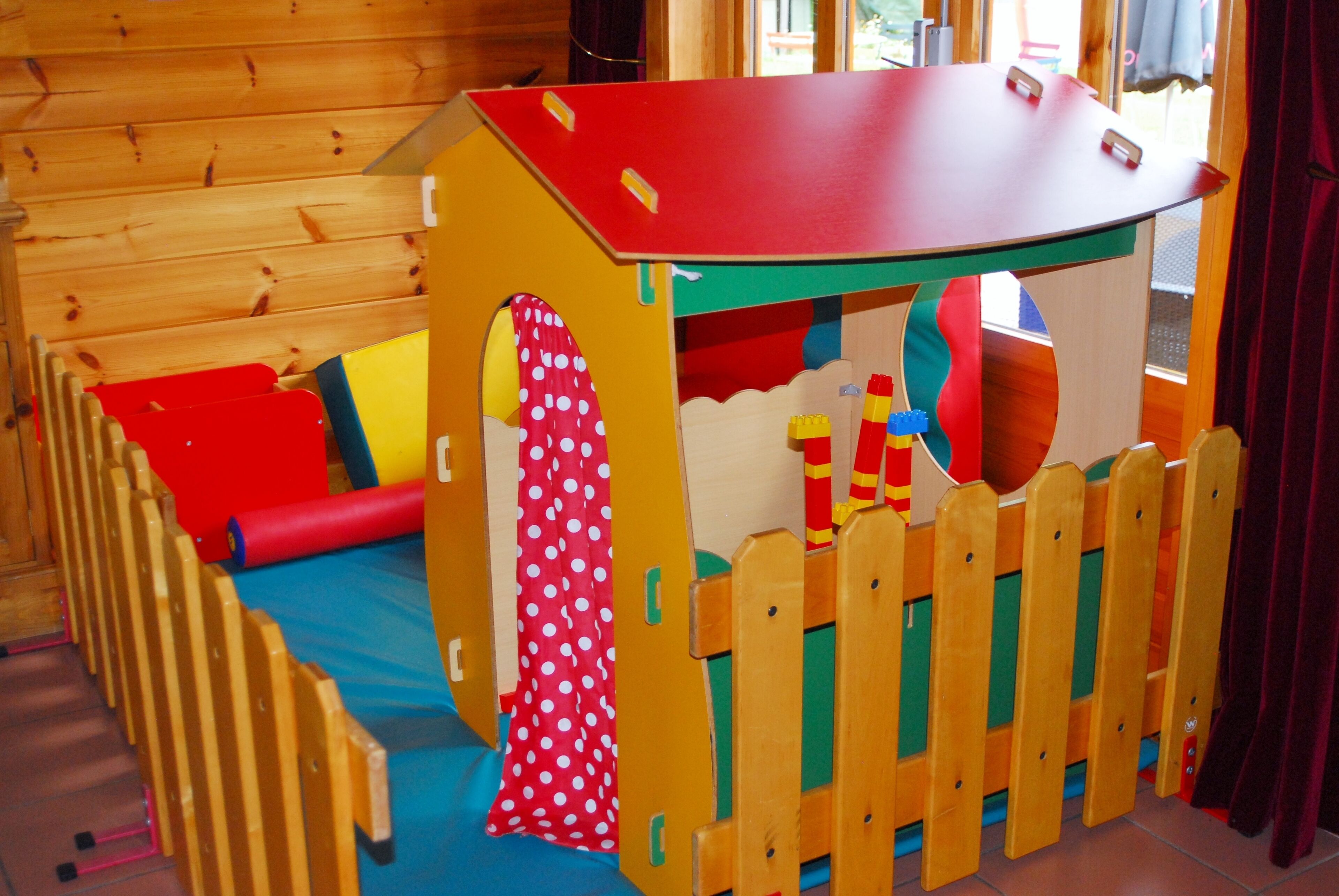 Uma casinha com telhado vermelho, cerca de madeira e chão azul.