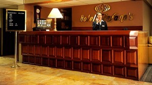 Bancada de recepção de hotel com tela digital exibindo uma mensagem de boas-vindas e um relógio.