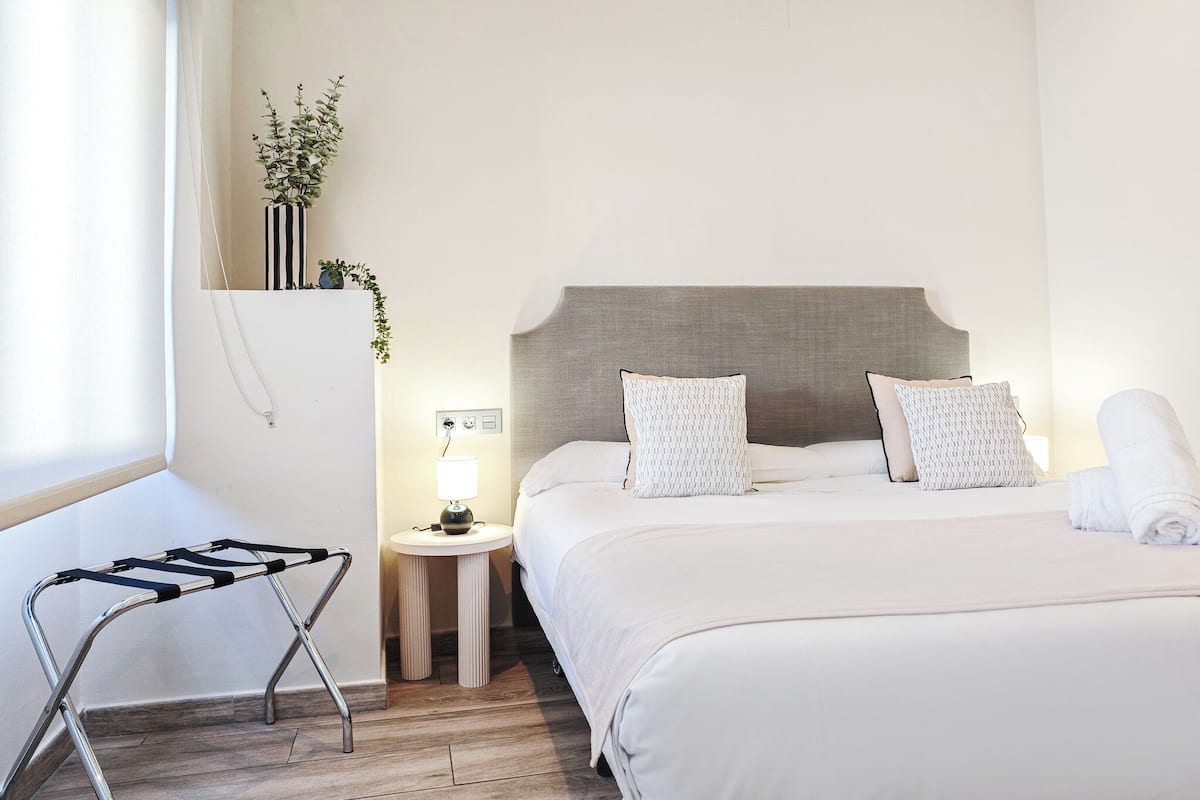 Quarto bem arrumado com uma cama grande, mesas de cabeceira, uma luminária e um varal.
