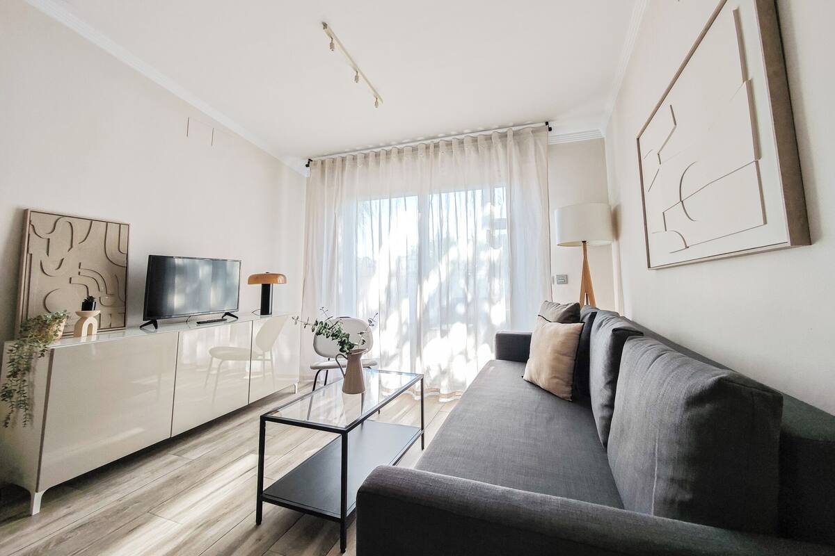 Uma sala de estar moderna com sofá, mesa de centro de vidro, televisão e armário.