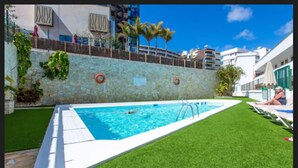 Piscina com muro de pedra e área gramada.