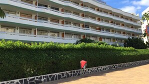 Um hotel com vários andares, varandas, uma parede de pedra e uma caixa de correio vermelha.
