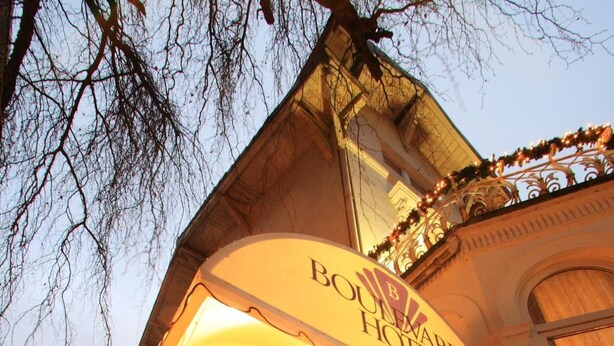 Exterior do Hotel Bodmer em Hamburgo, exibindo um estilo arquitetônico clássico com uma entrada em arco notável e decorações natalinas festivas.