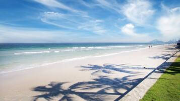 Na praia, praia de areia branca, guarda-sóis de praia, toalhas de praia