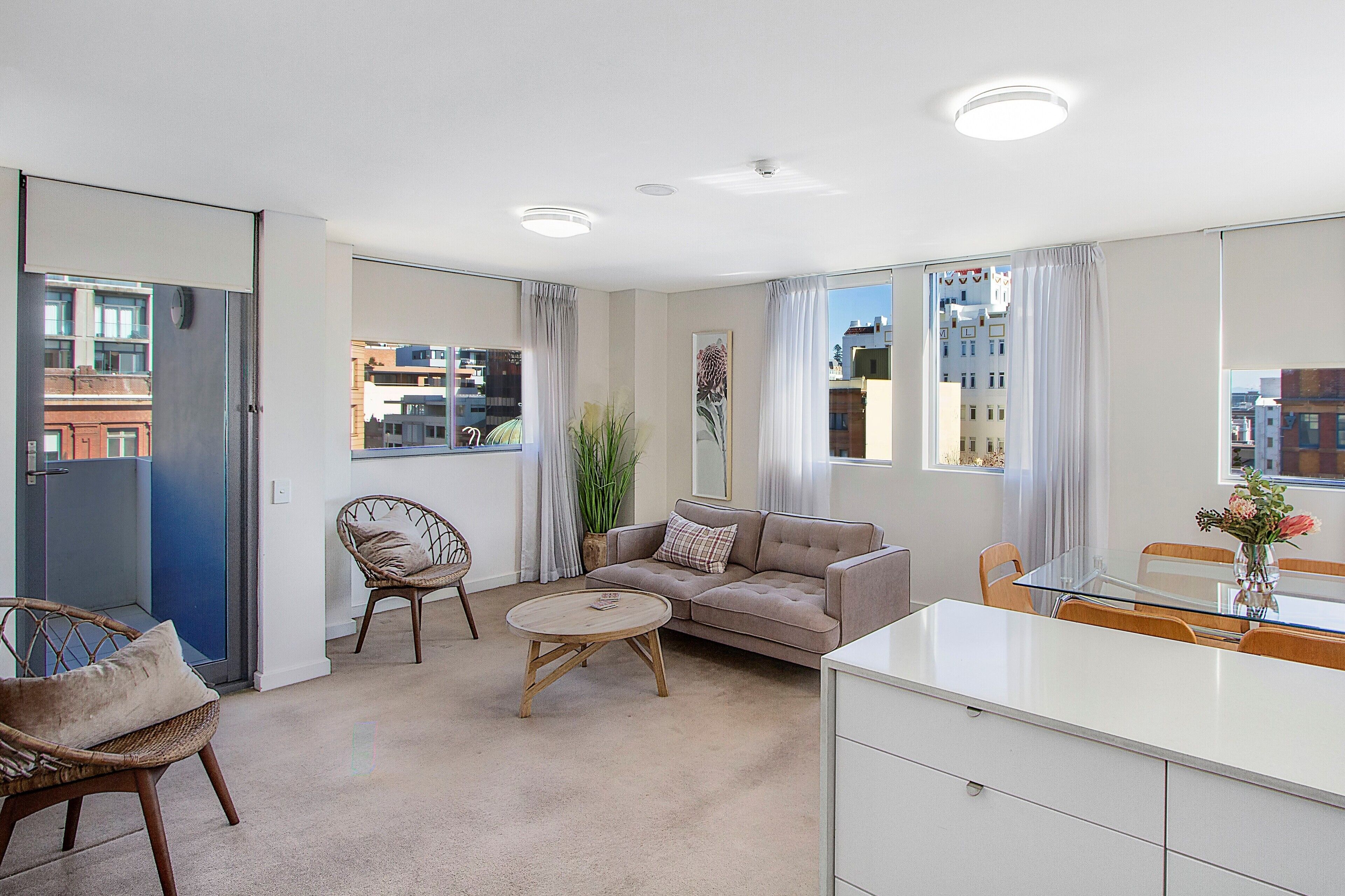 Uma sala de estar moderna com sofá, cadeiras, mesa de centro e área de jantar com mesa e cadeiras.